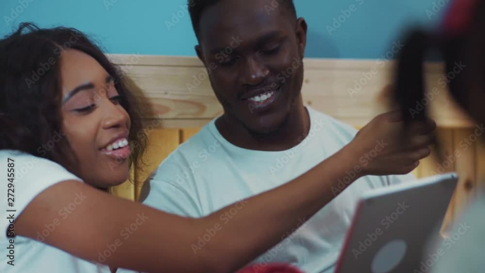 Lovely young african american family using a touch tablet lying on bed ...
