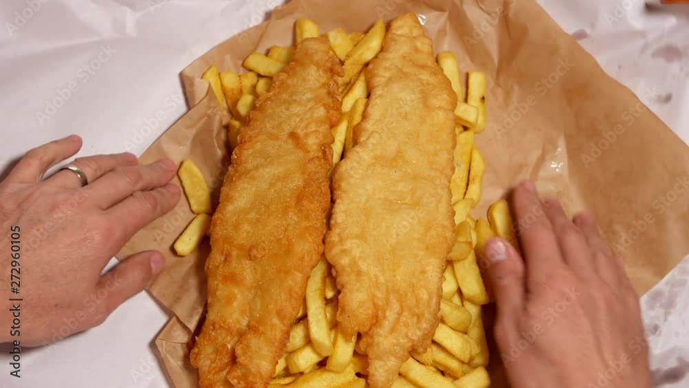 Man opens paper wrapper with fish and chips inside. TOP DOWN ANGLE ...