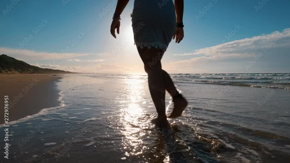 Slow motion shot of womans torso relaxed walk in shallow water along ...