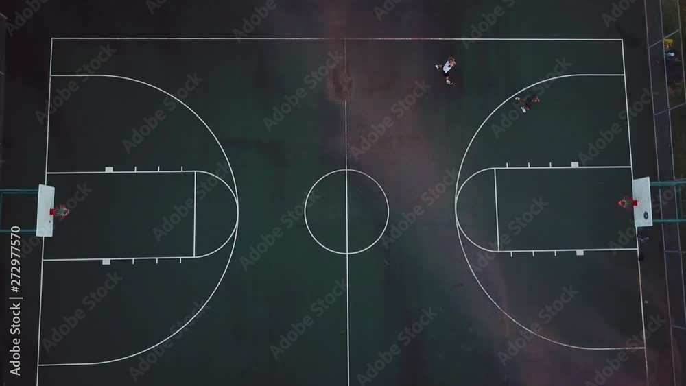 Drone Shot directly above a local, outdoor basketball court where two ...