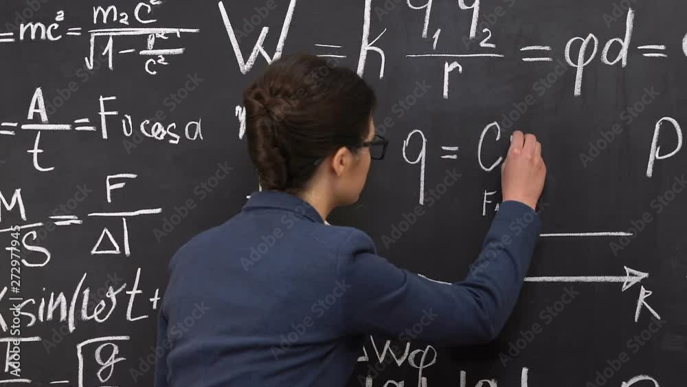 Female teacher writing physical formulas on blackboard, exact science ...