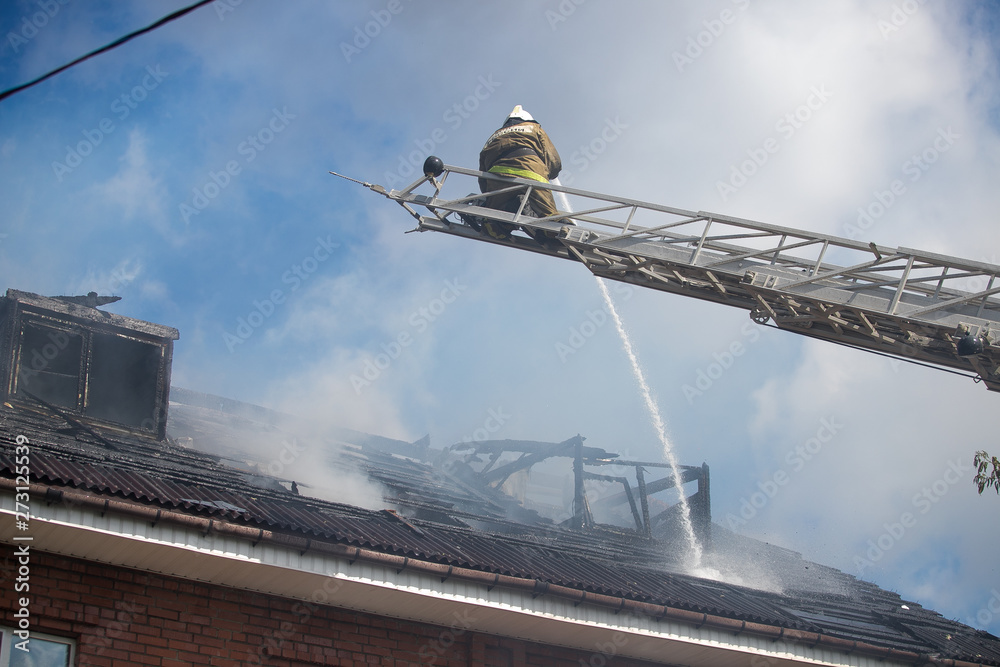 Foto de Smoldering remains of a ghetto house with a fireman spraying ...