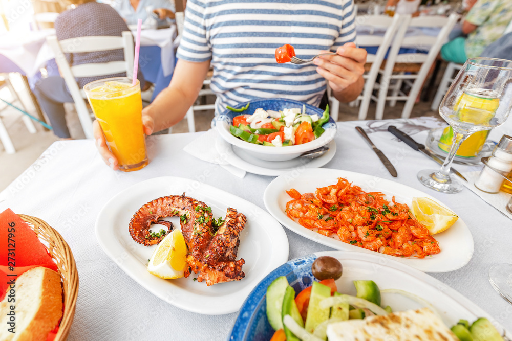 Close-up of a man eating delicious seafood - shrimp and octopus grilled ...