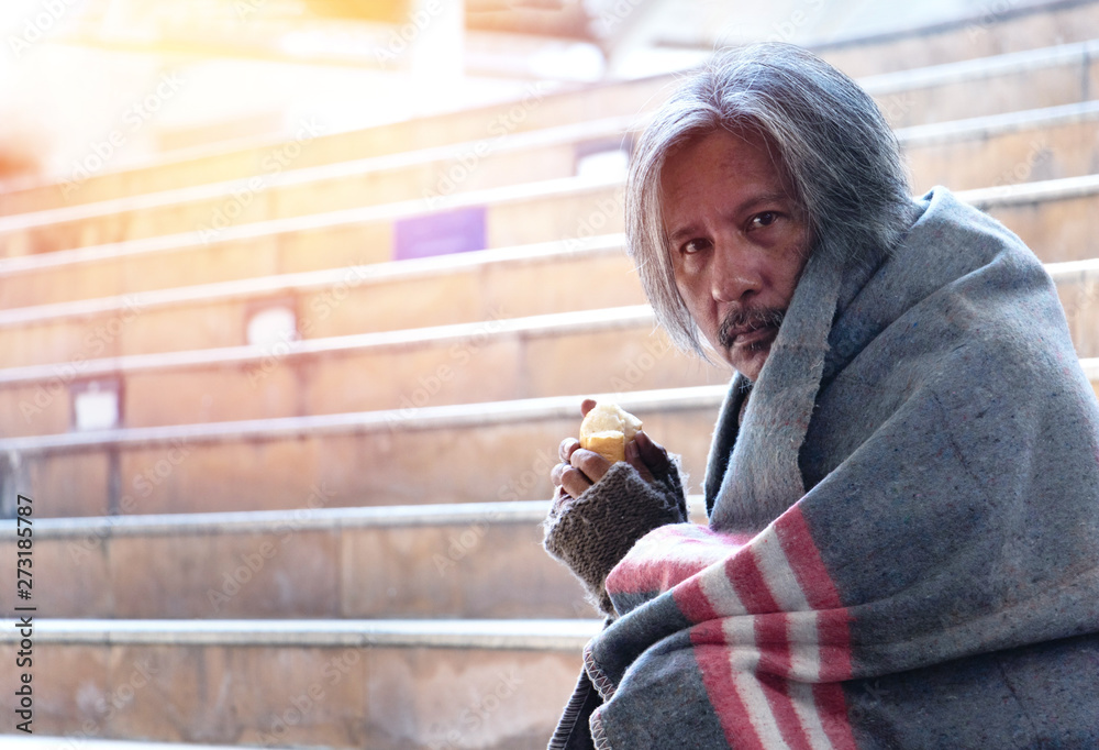 Homeless man is sitting down on staircase and walkway in town.He is ...