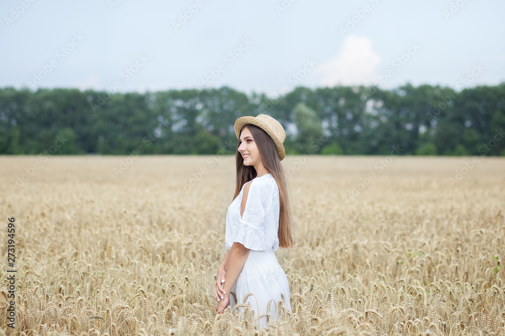 A young girl in a hat is a boatman enjoying the nature of a wheat field ...