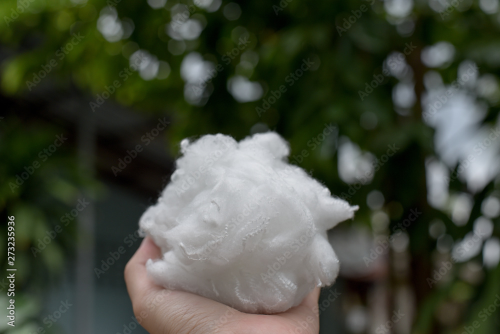 Hands holding polyester fiber with green blurred background.save ...