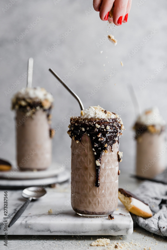 Black and white milkshake. A hand sprinkles a topping on a milkshake ...