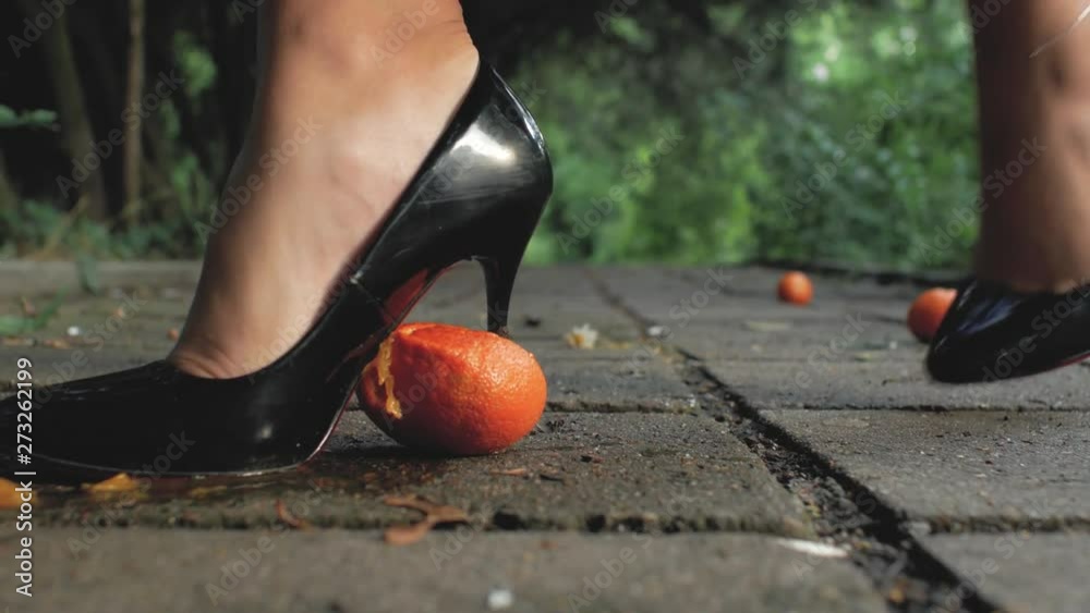 foot girl close up in black patent-leather shoes crushed a mandarin on ...
