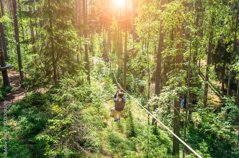 Anonymous man flying above a pine tree forest on a roulette wheel ...