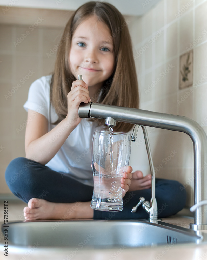 Portrait of a little caucasian girl gaining a glass of tap clean water ...