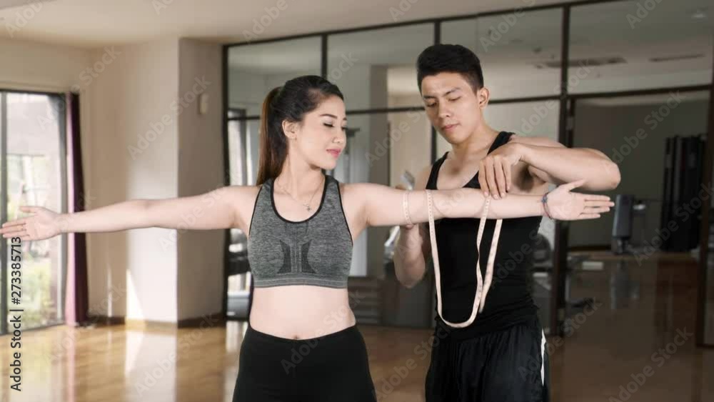 Young woman measuring arms muscle with her personal trainer using a ...