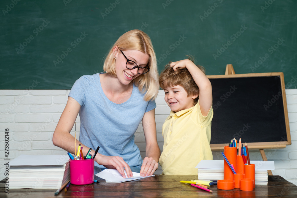 Back to school. Teacher helping kids with their homework in classroom ...