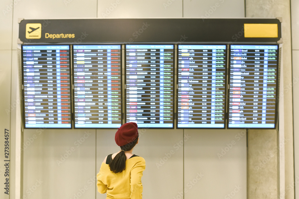 Passenger checking flight status at airport information display, Asian ...