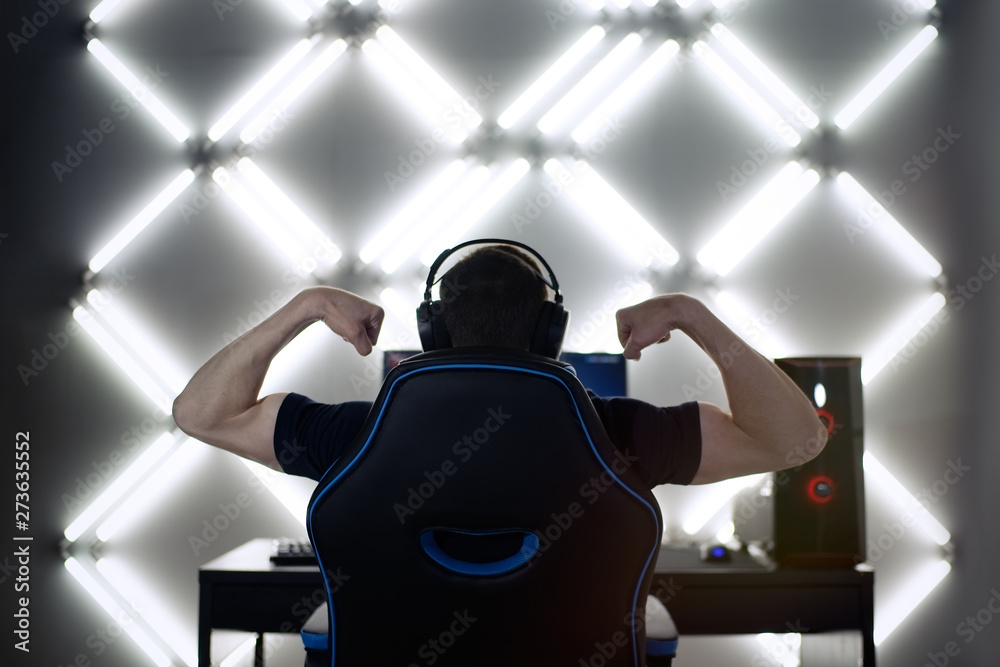 Back view of young gamer guy in headphones screaming and rejoicing ...