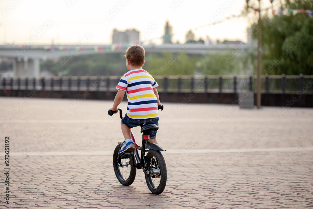 Active preschool kid boy without helmet biking on bicycle in the city ...