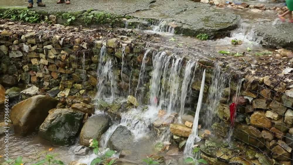 Rainwater flowing through rocks after the rain stops. Children playing ...