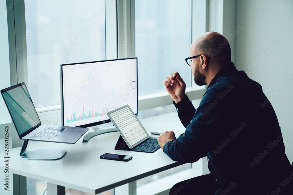 Young man employee working on PC and laptop computers with financial ...