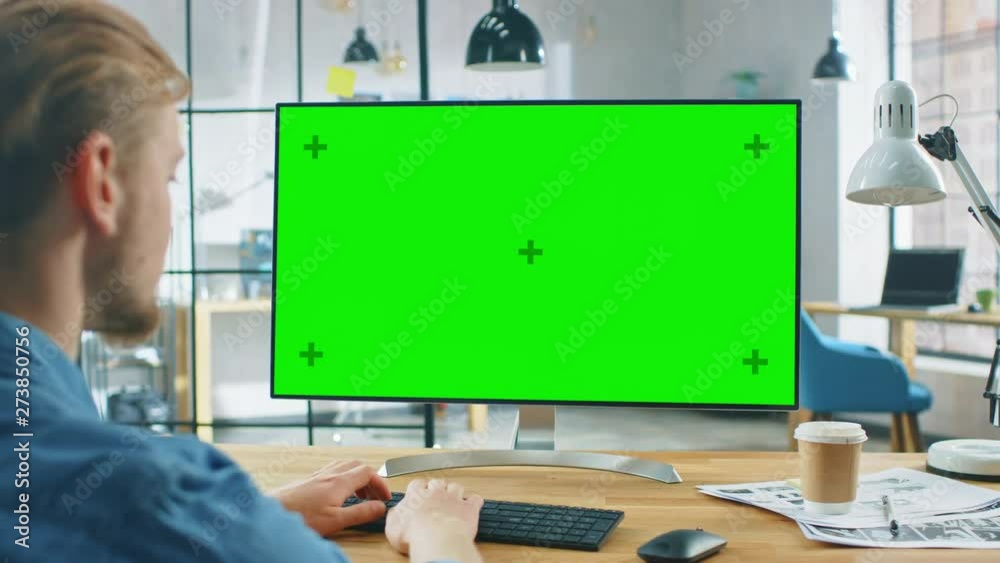 Over the Shoulder Shot: Man Uses Laptop Computer with Green Mock-up ...