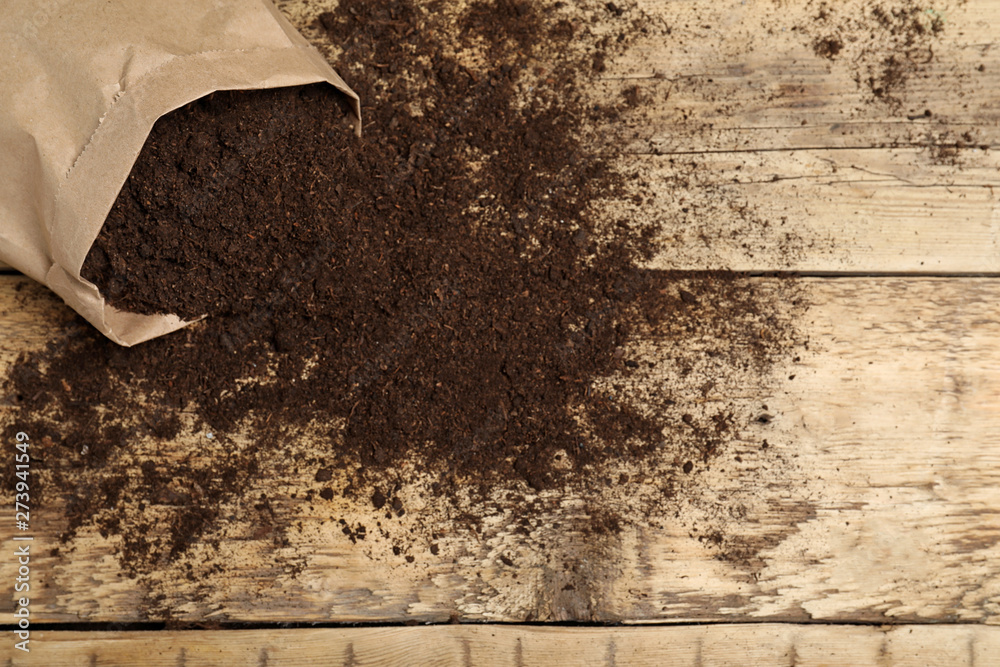 Paper bag and soil on wooden table, top view with space for text ...