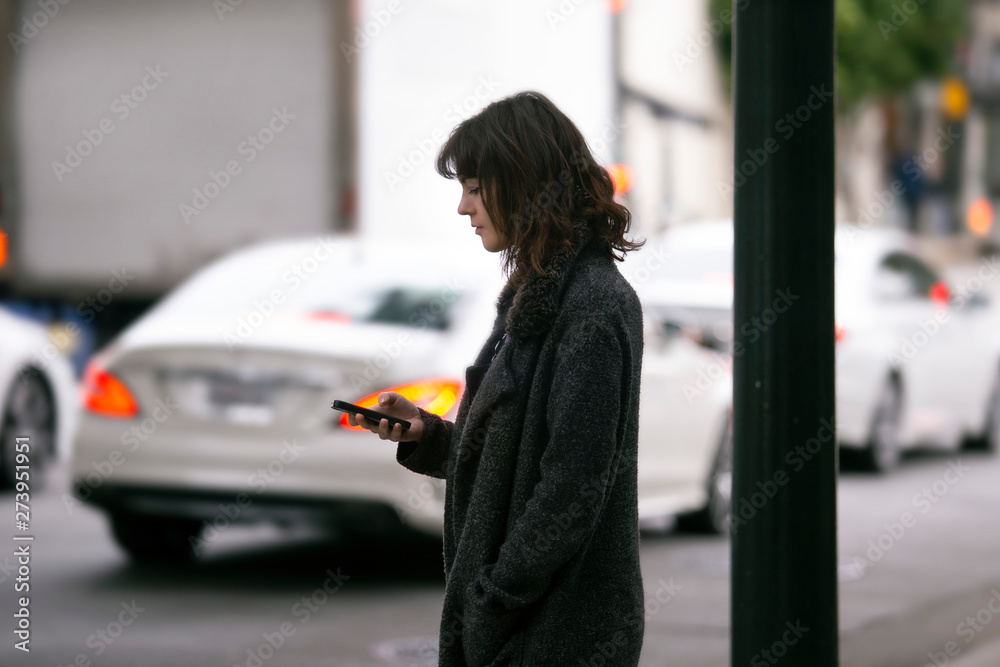 Female pedestrian waiting for a rideshare. She is sharing her gps ...