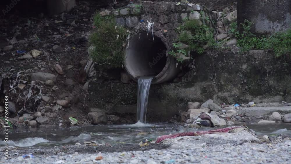 Polluted water falling in river from drainage pipe. A polluted river of ...