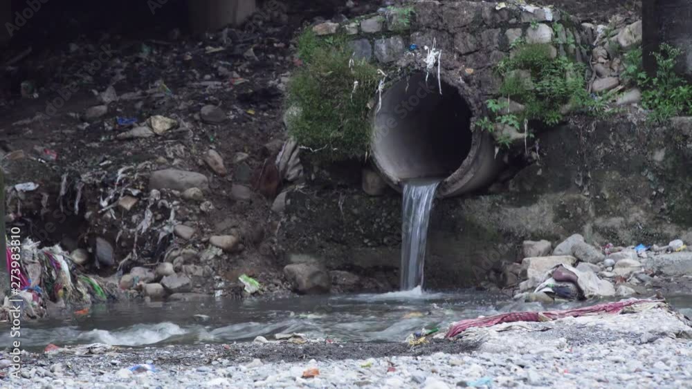 Polluted water falling in river from drainage pipe. A polluted river of ...