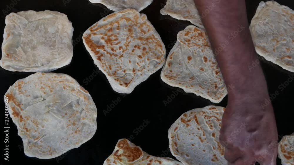 Chef making a lot of traditional Indian food called 'Roti Canai'. 4k ...