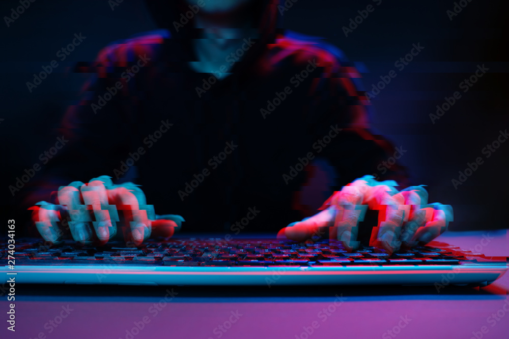 Hacker in the hood working with computer typing text in dark room ...