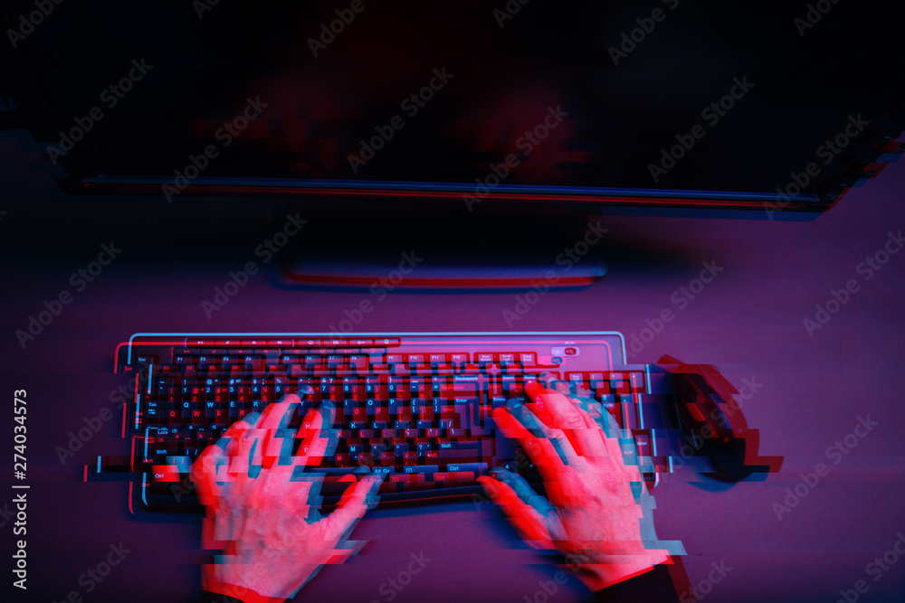 Hacker in the hood working with computer typing text in dark room ...