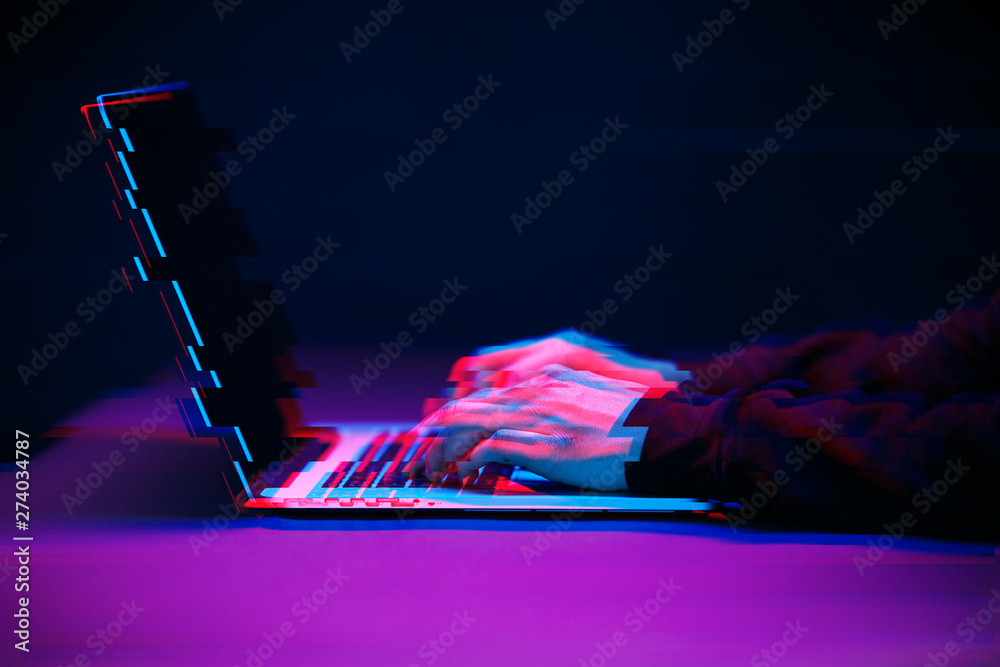 Hacker in the hood working with laptop typing text in dark room. Image ...
