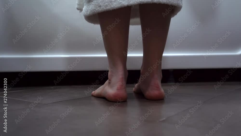 Women's feet go into the bathroom,stop at the bathroom, a white robe ...