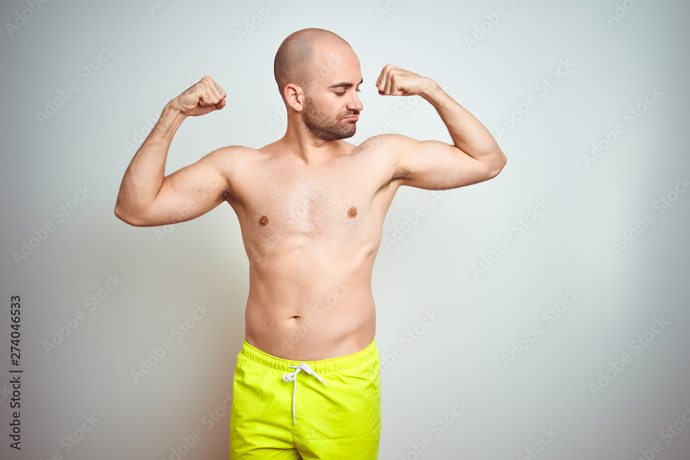 Young shirtless man on vacation wearing yellow swimwear over isolated ...
