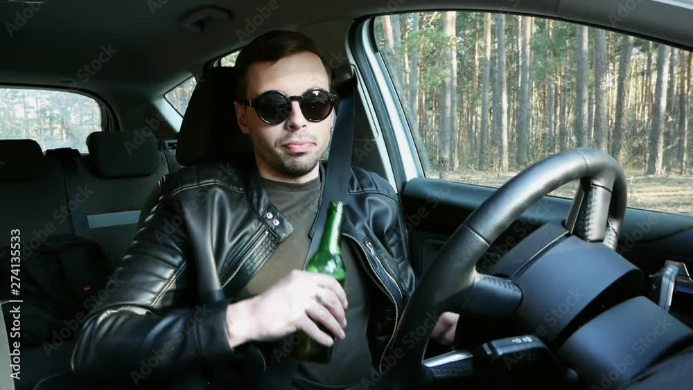 Drunk driver drinking beer in the car on on a country road, falls ...