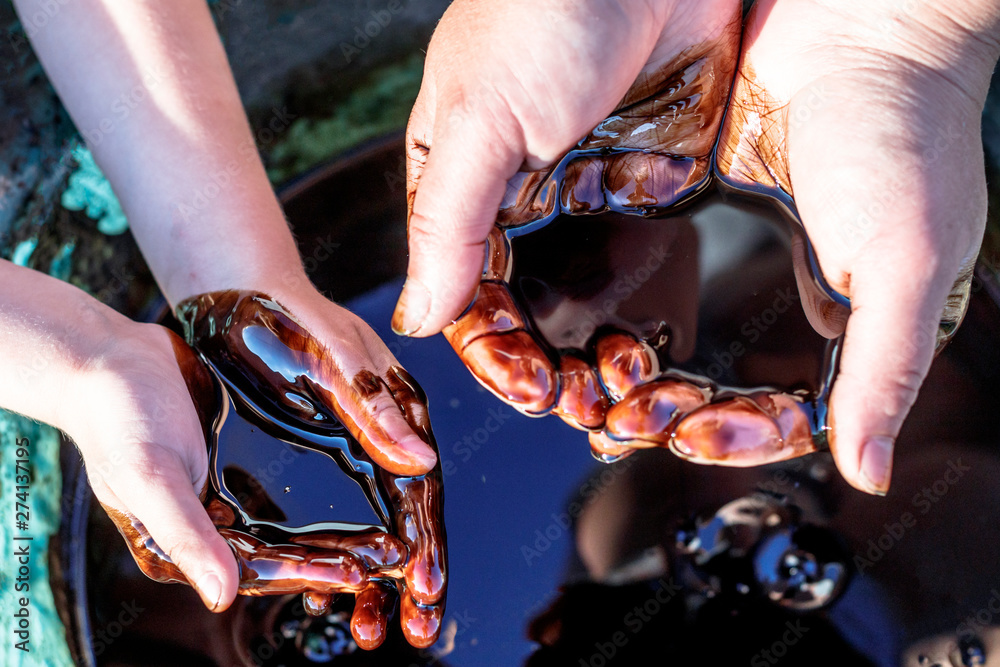 woman and little girl hands in it black oil. there is tonirvkak. close ...
