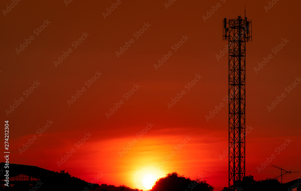 Beautiful red and orange sunset sky. Silhouette telecommunication tower and tree in the evening ...
