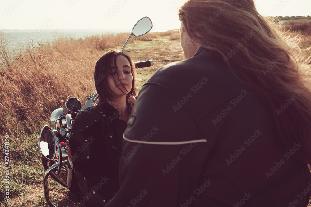 Romantic biker couple in leather on red motorcycle kissing and hugging ...