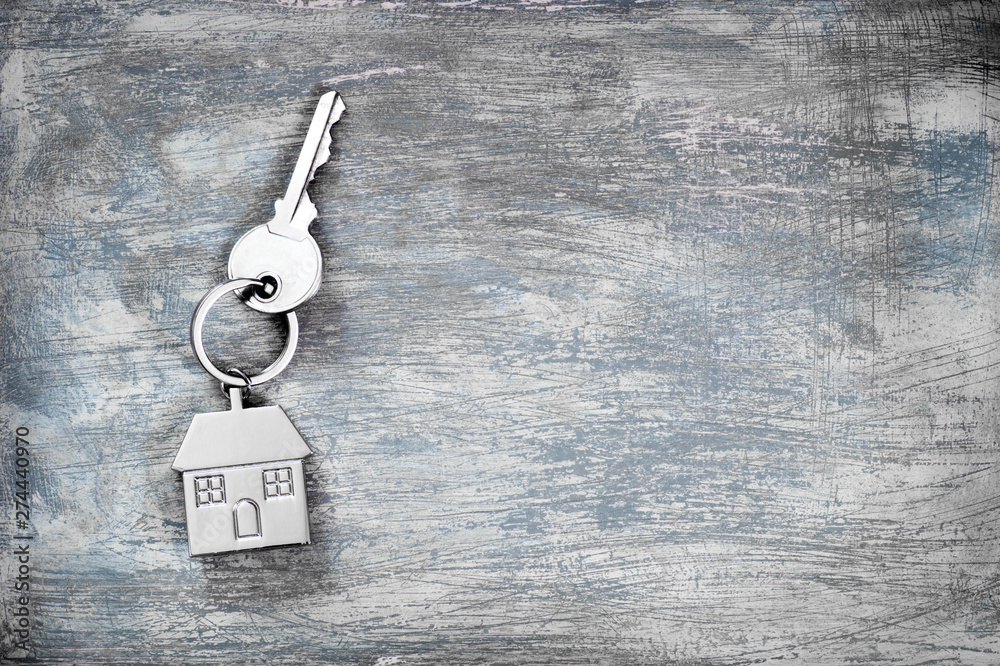 The symbol of a metal house with a key on a scratched concrete gray ...