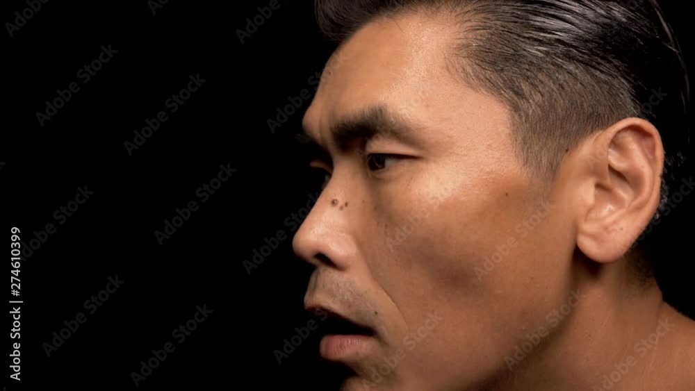 This slow motion video shows the profile of an asian man as he is ...