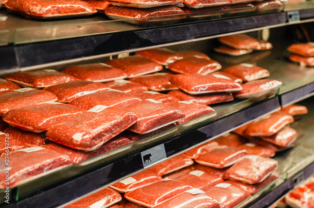 meats packed and stacked on the shelves of the supermarket for retail ...