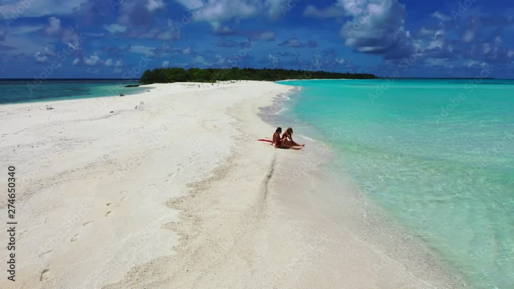 attractive girls in bikinis sitting on tropical beach in white sand ...