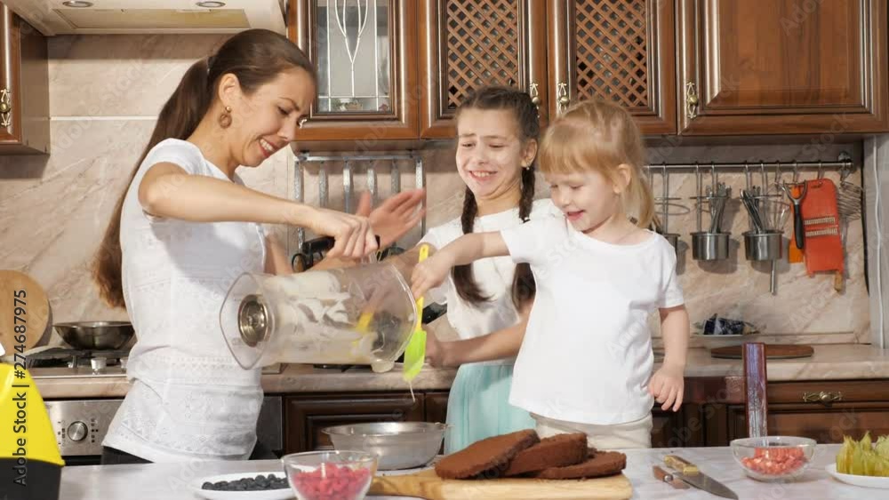 Daughters helps her mom to cook cream for cake, they eats and tastes ...