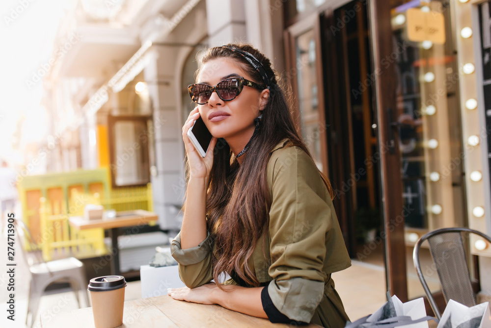 Elegant girl with long dark hair calling someone while resting in ...