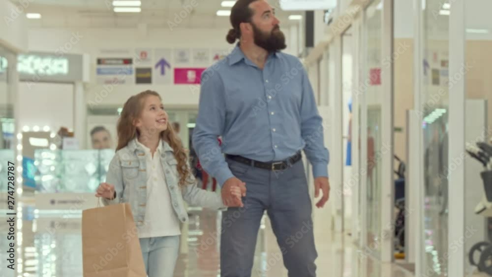 Loving father walking at shopping mall with his adorable little ...