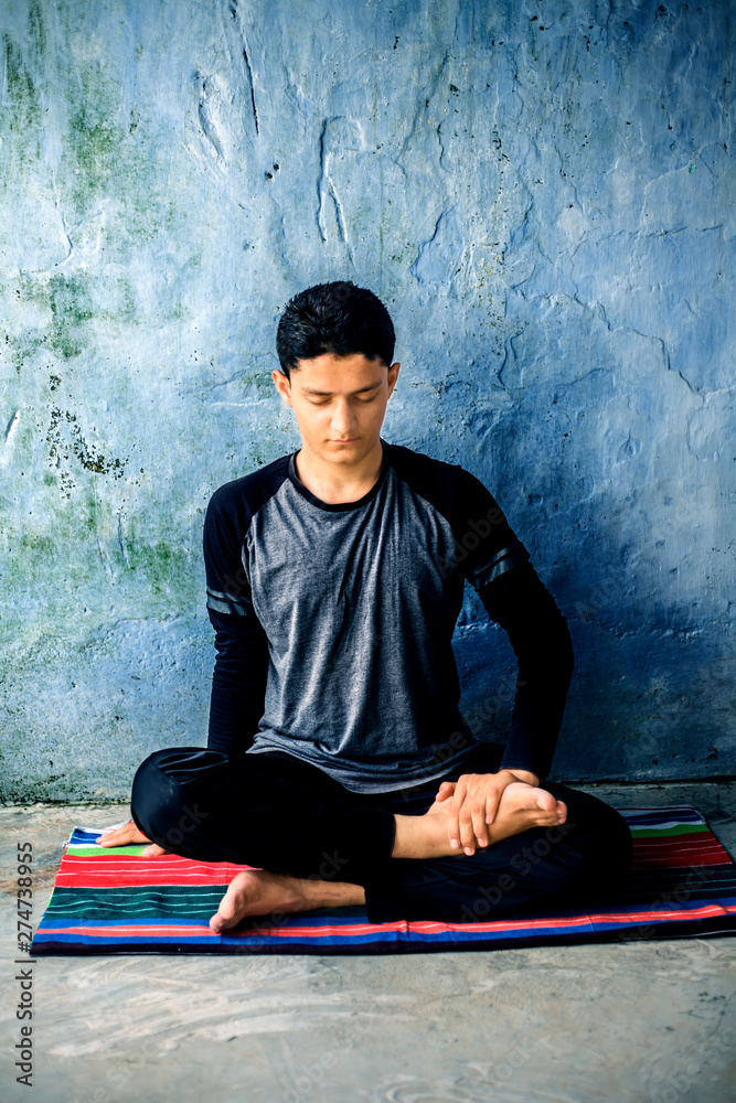 Teenage boy wearing black colored attire and doing yoga on colorful ...