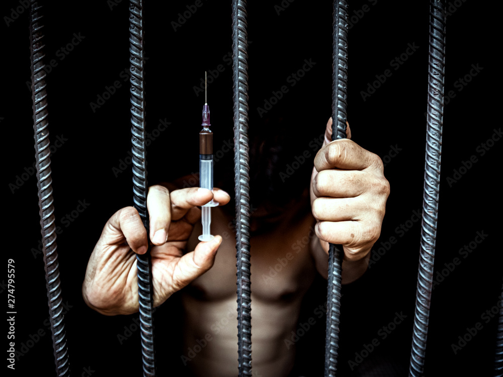 Drugs and prison cell concept. Drug addict man with syringe using drugs ...