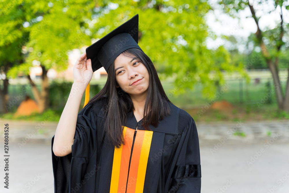Portrait of a female university graduate wears black academic gown and ...