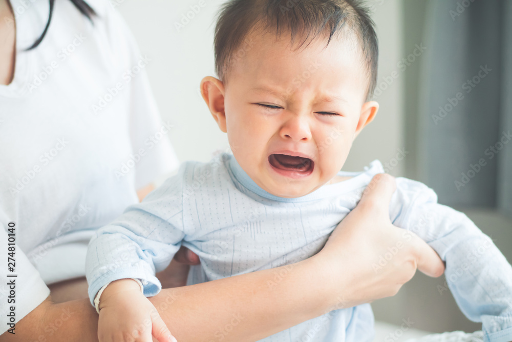 Crying baby in his mother's hand in bedroom with copy and space. Stock ...
