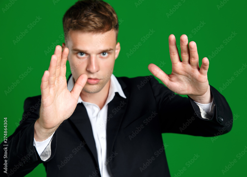 Man holds his hands in front of him in a suit on a green background ...
