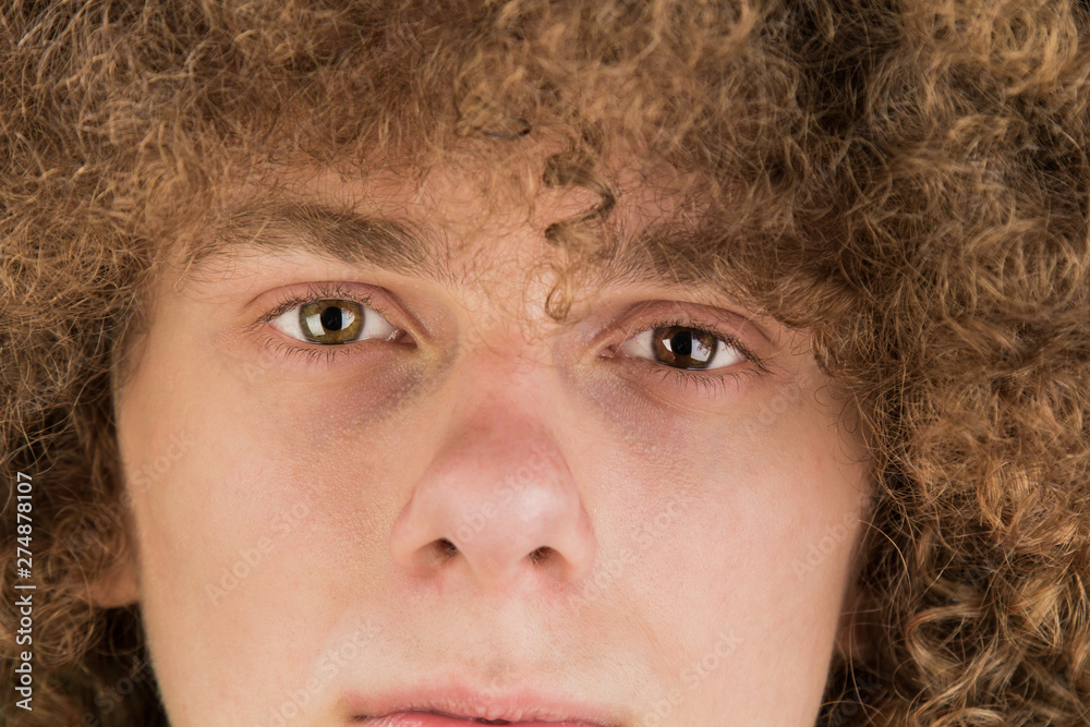 Cropped portrait of a young curly European man with long curly hair and ...