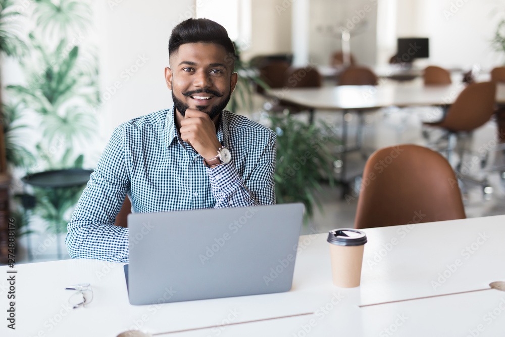 Young indian man smiling and working at modern office Stock Photo ...